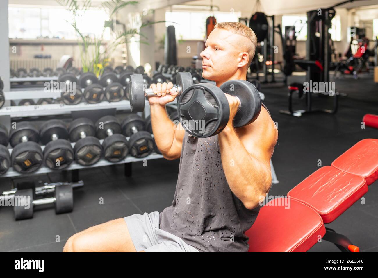 Young fit man in a gym exercising with dumbbells.healthy man working ...