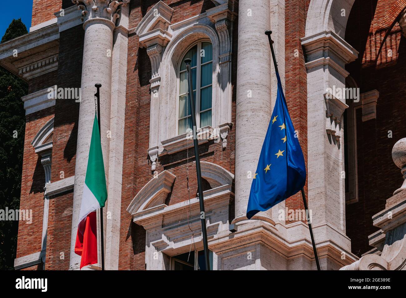 Closeup of the Italian and EU flags in front of a government brick ...
