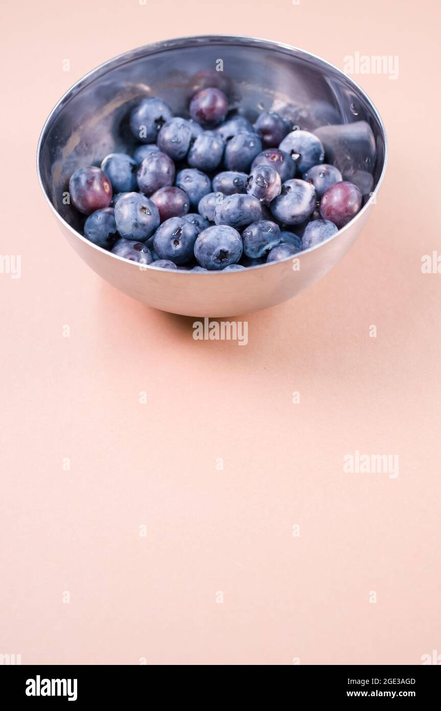 Vertical closeup of a small bowl of blueberry on the aesthetic peach ...