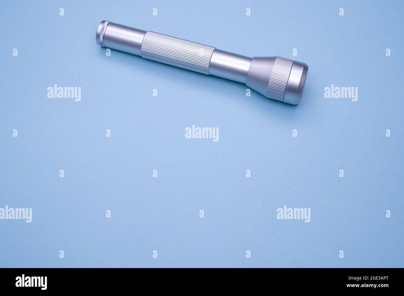 Closeup of a metallic flashlight on the aesthetic blue background Stock ...