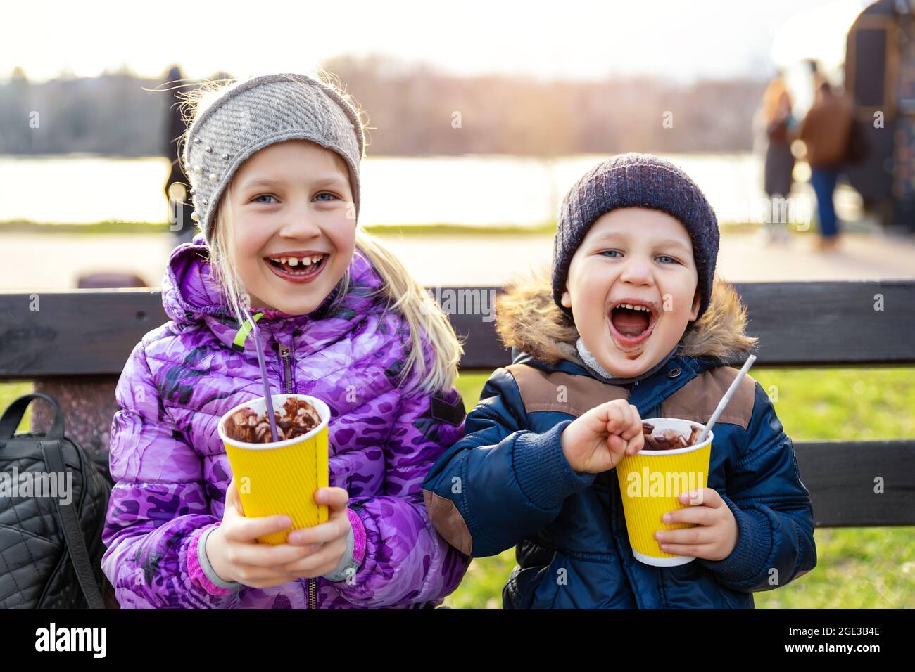 Two cute adorable siblings children sitting on bench drink delicious ...
