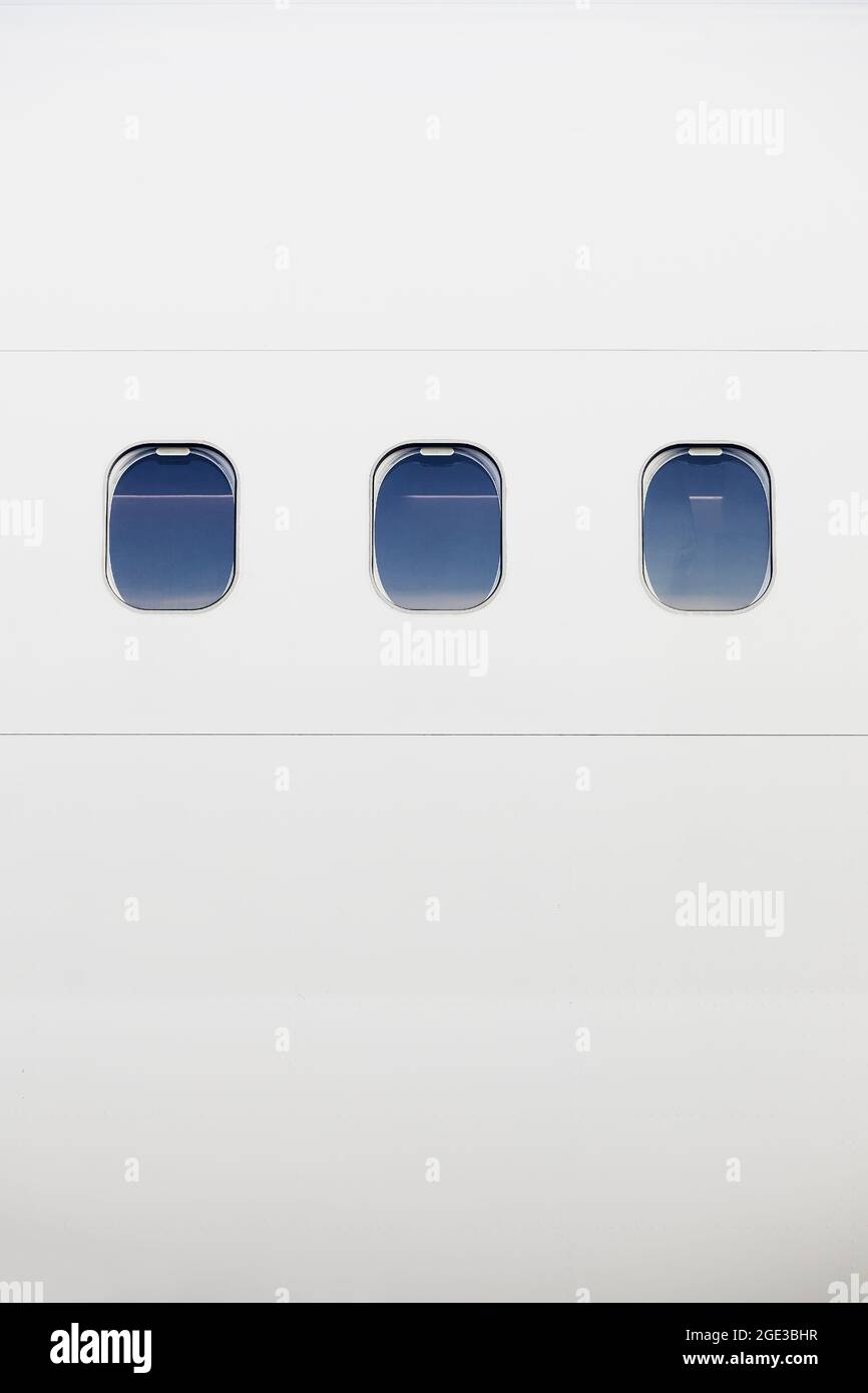 Three windows on fuselage of white airplane. Vertical image of plane ...