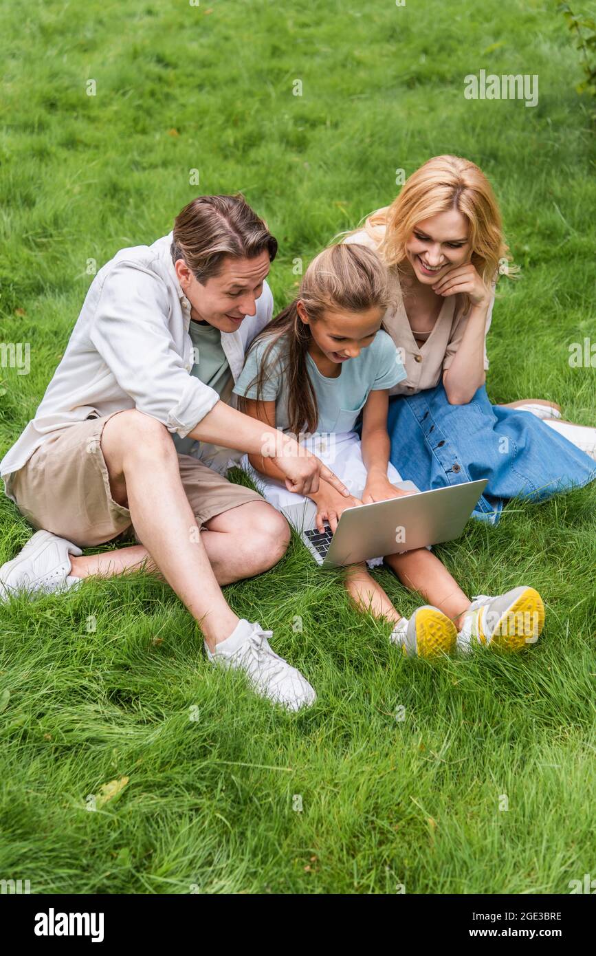 High angle view of man pointing with finger at laptop near wife and ...