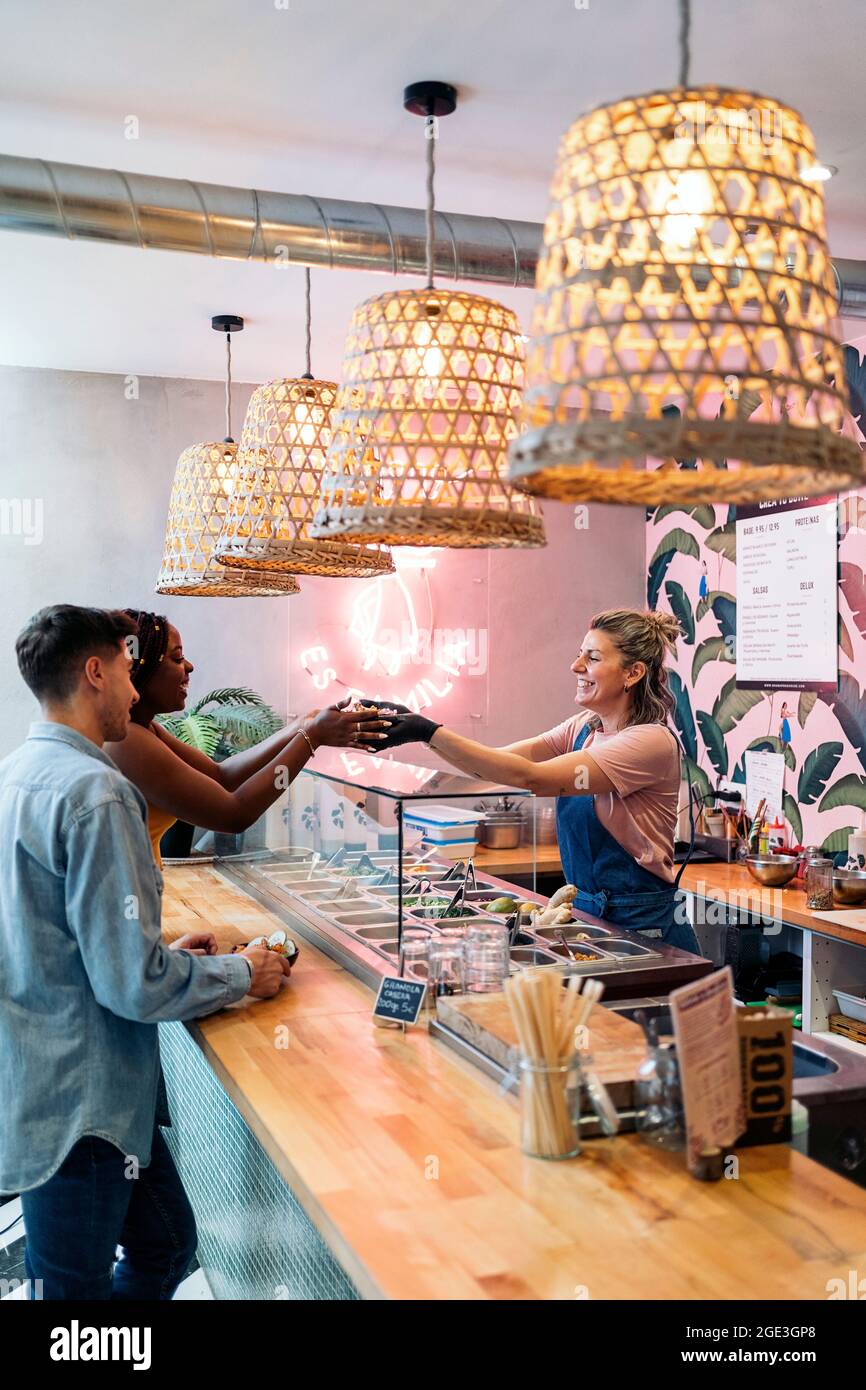 African american woman and her friend buying a poke bowl in a cool ...