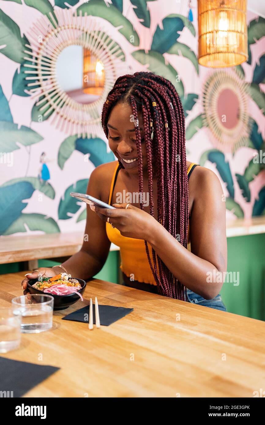 Beautiful african woman sitting in a restaurant enjoying a healthy poke ...