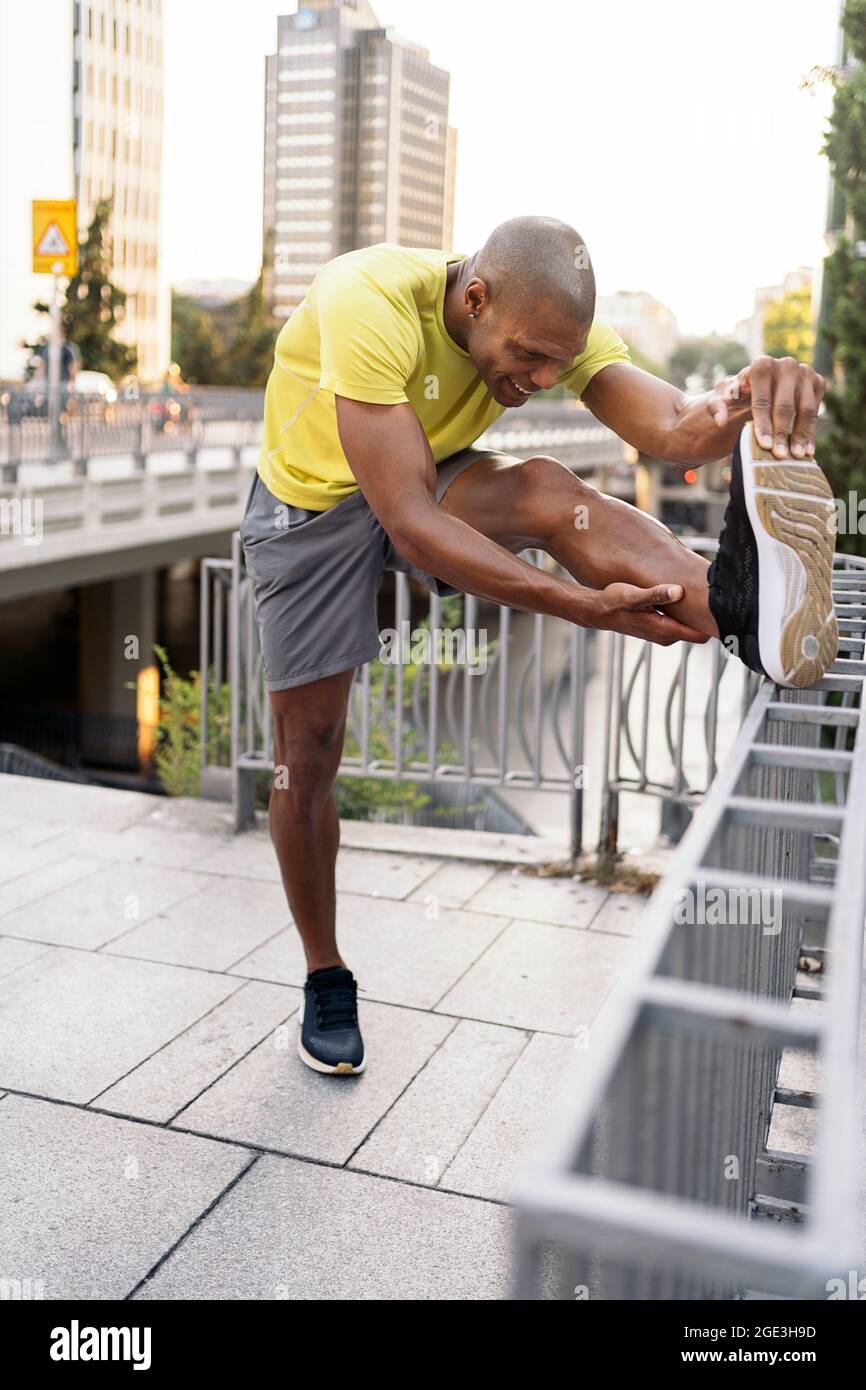 Front side view of African American man stretching his left leg over ...