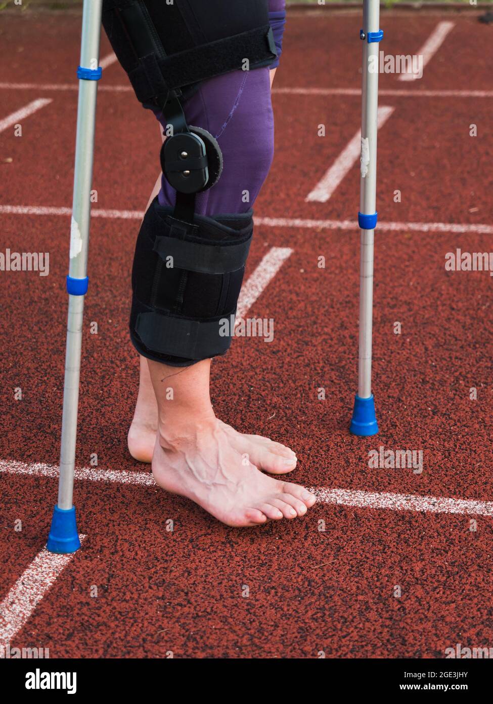 Hurt runner walk by forearm crutches on red running track after ...