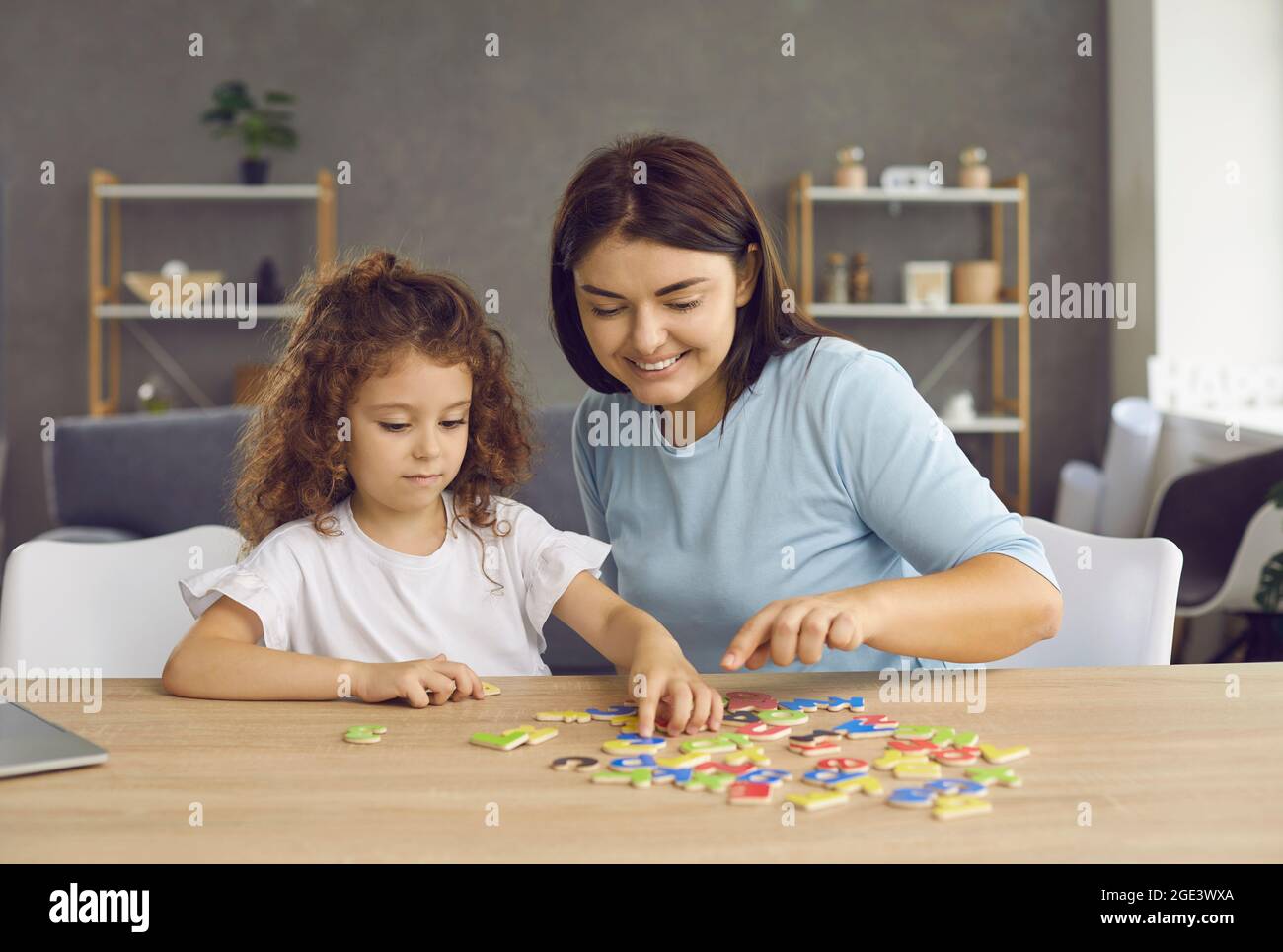 Happy little girl learning the English alphabet with her mom, teacher ...