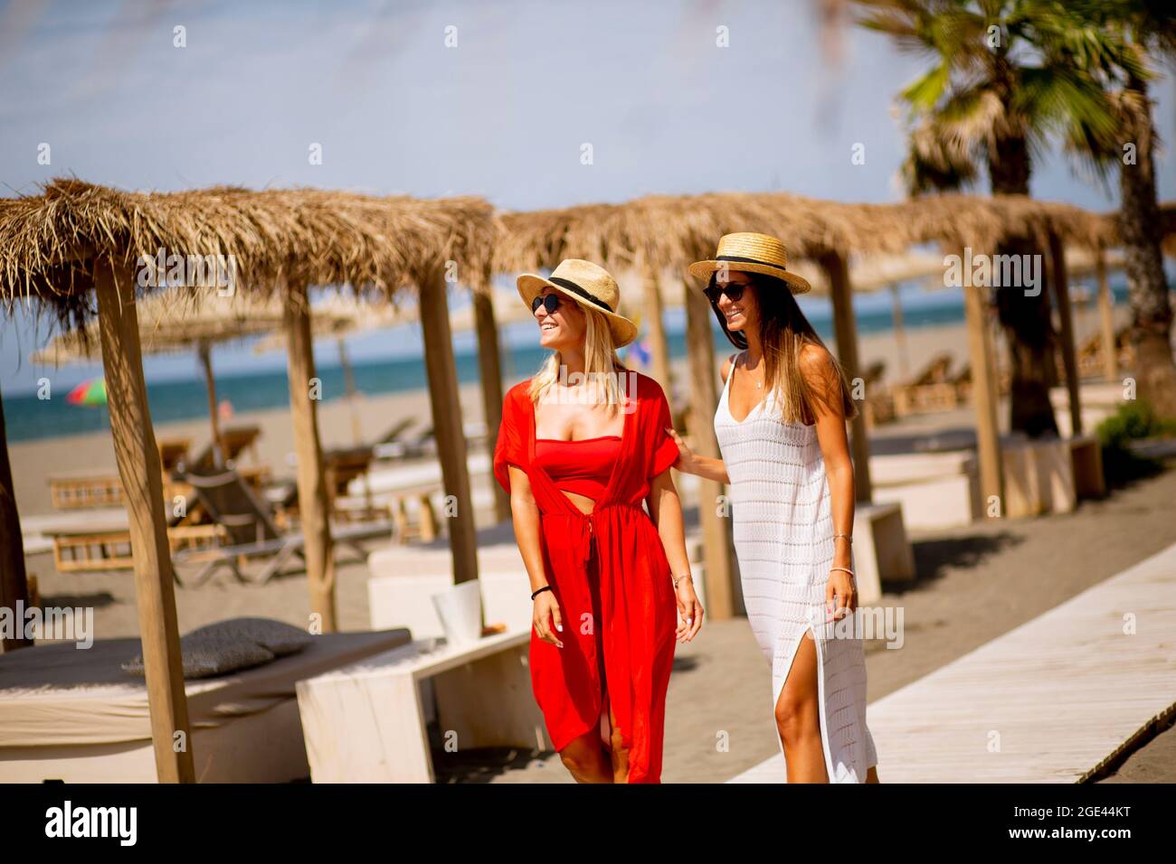 Two pretty young women walking on a beach at summer Stock Photo - Alamy