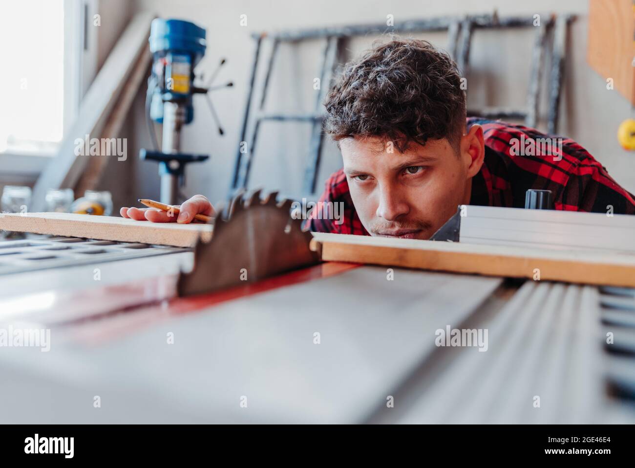 Young caucasian carpenter carefully cutting wood Stock Photo - Alamy