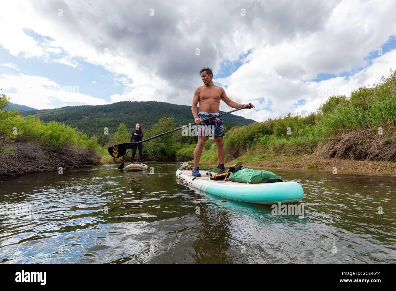 Adventurous people paddle boarding in a river Stock Photo - Alamy