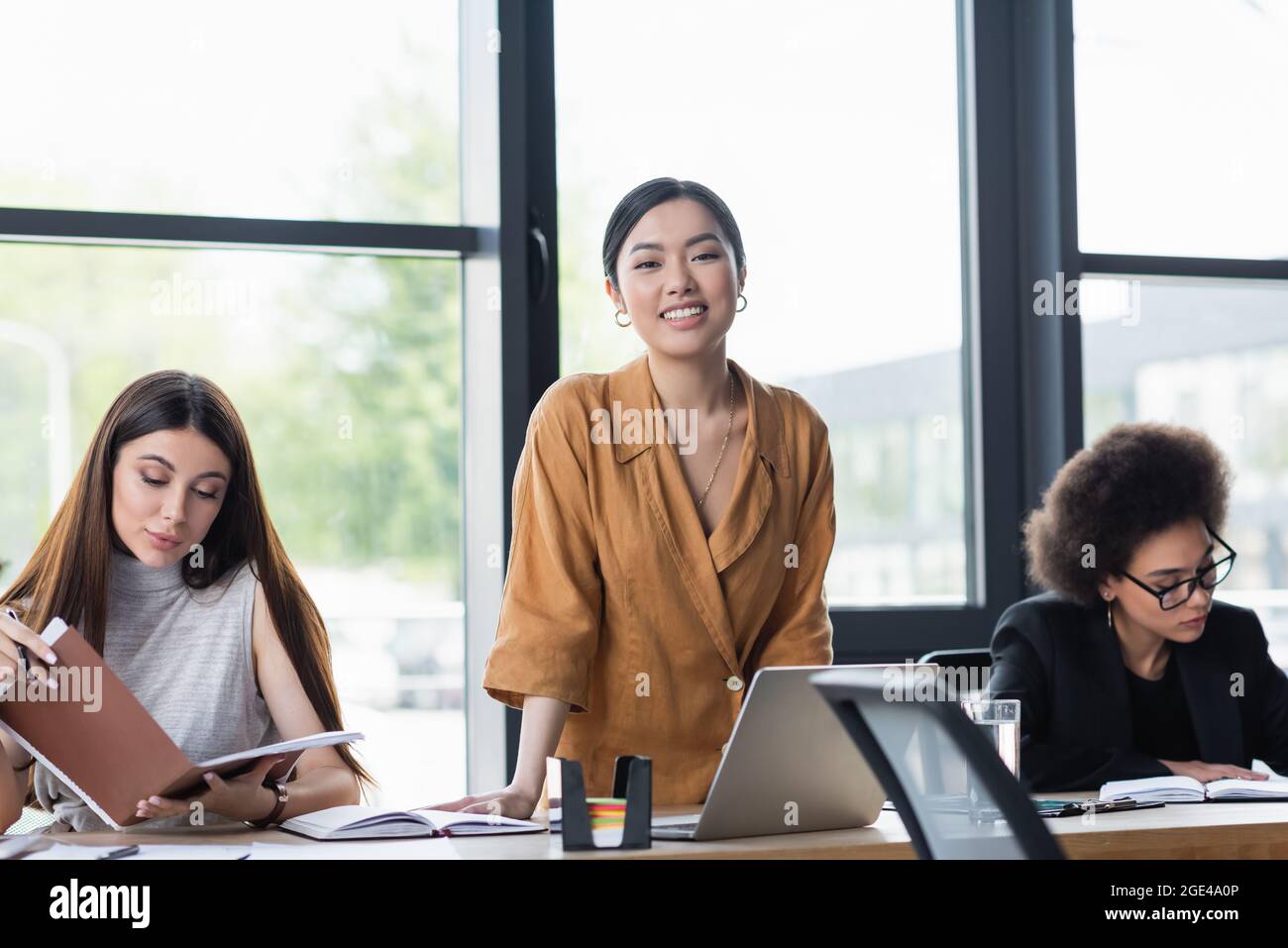 happy asian manager smiling at camera near interracial colleagues at ...