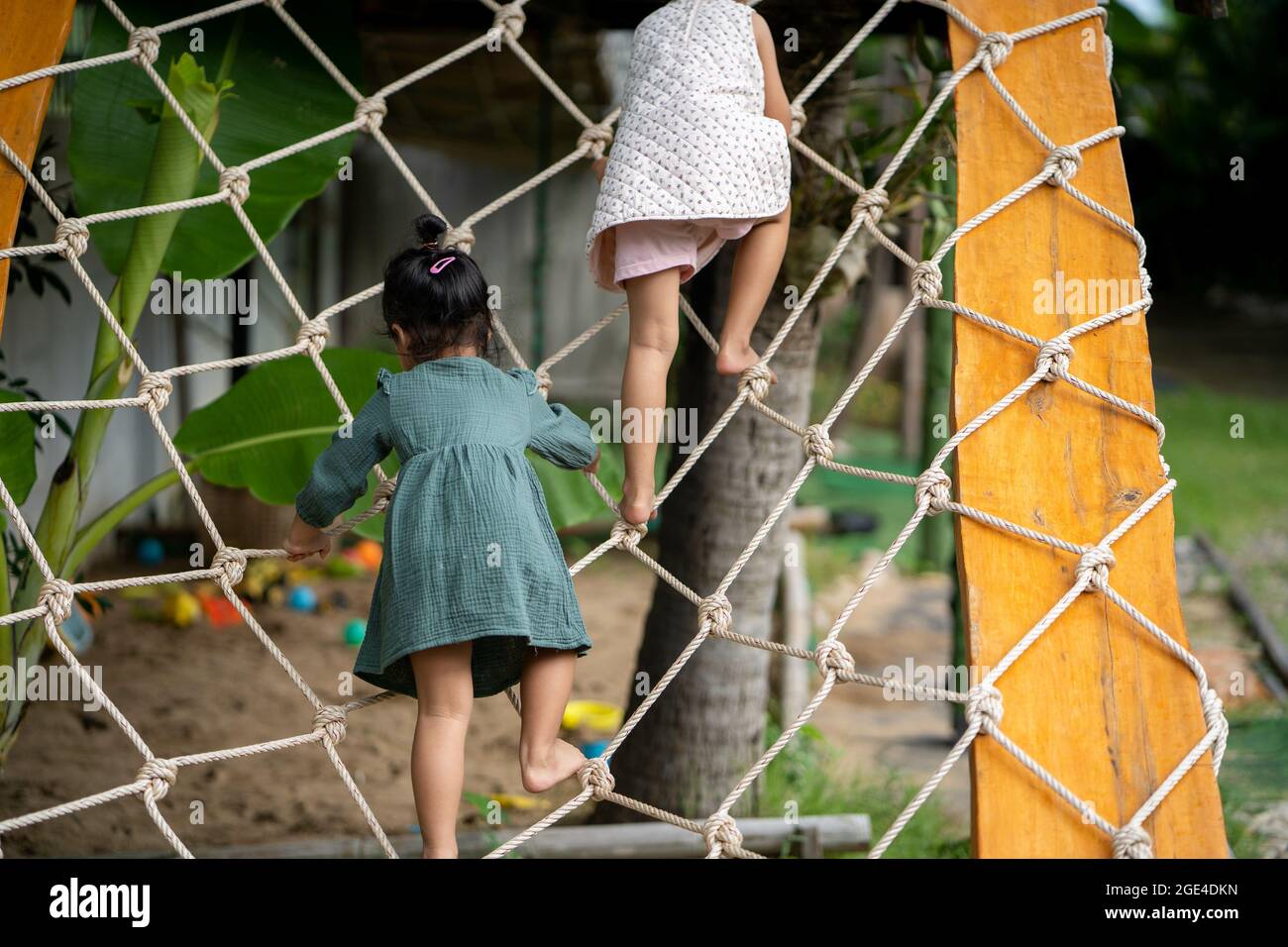 Rearview of little girls climbing on a rope web in the playground Stock ...