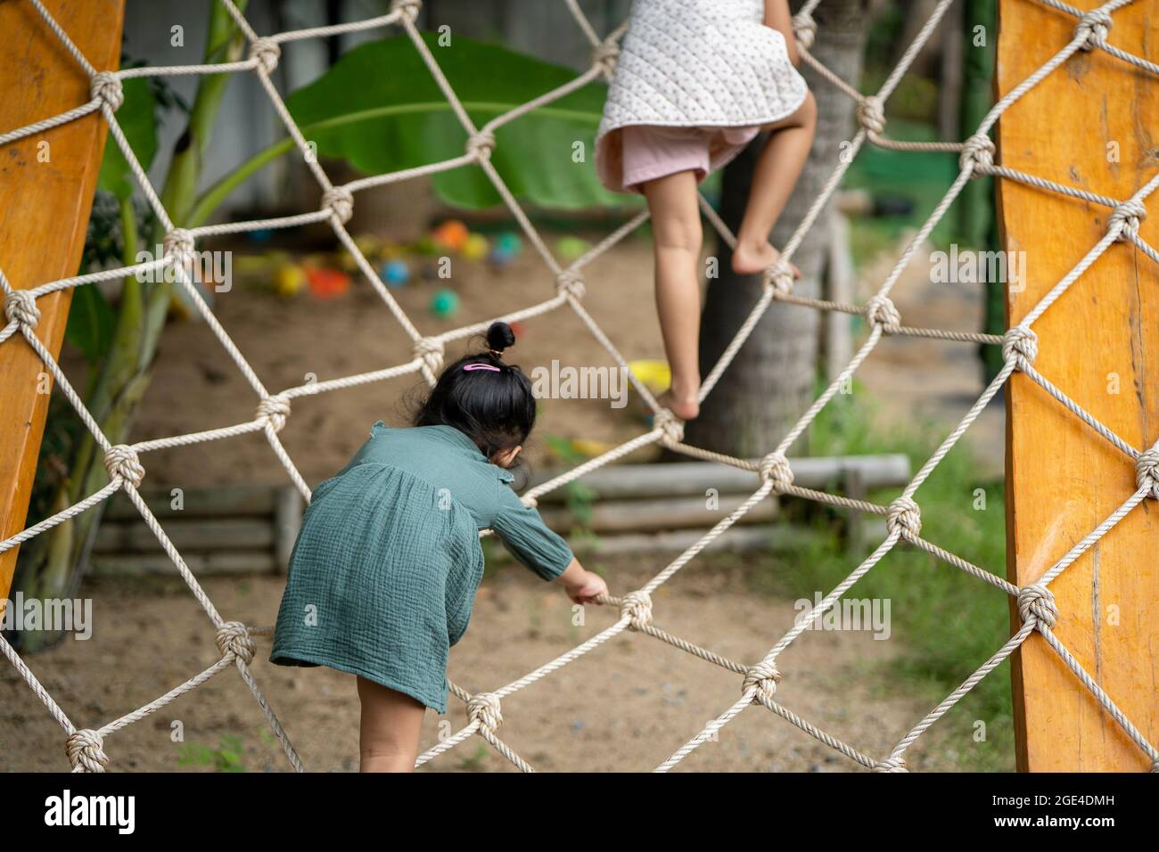 Rearview of little girls climbing on a rope web in the playground Stock ...