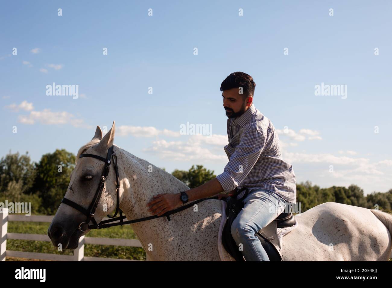 The handsome man rides a horse on a ranch Stock Photo - Alamy