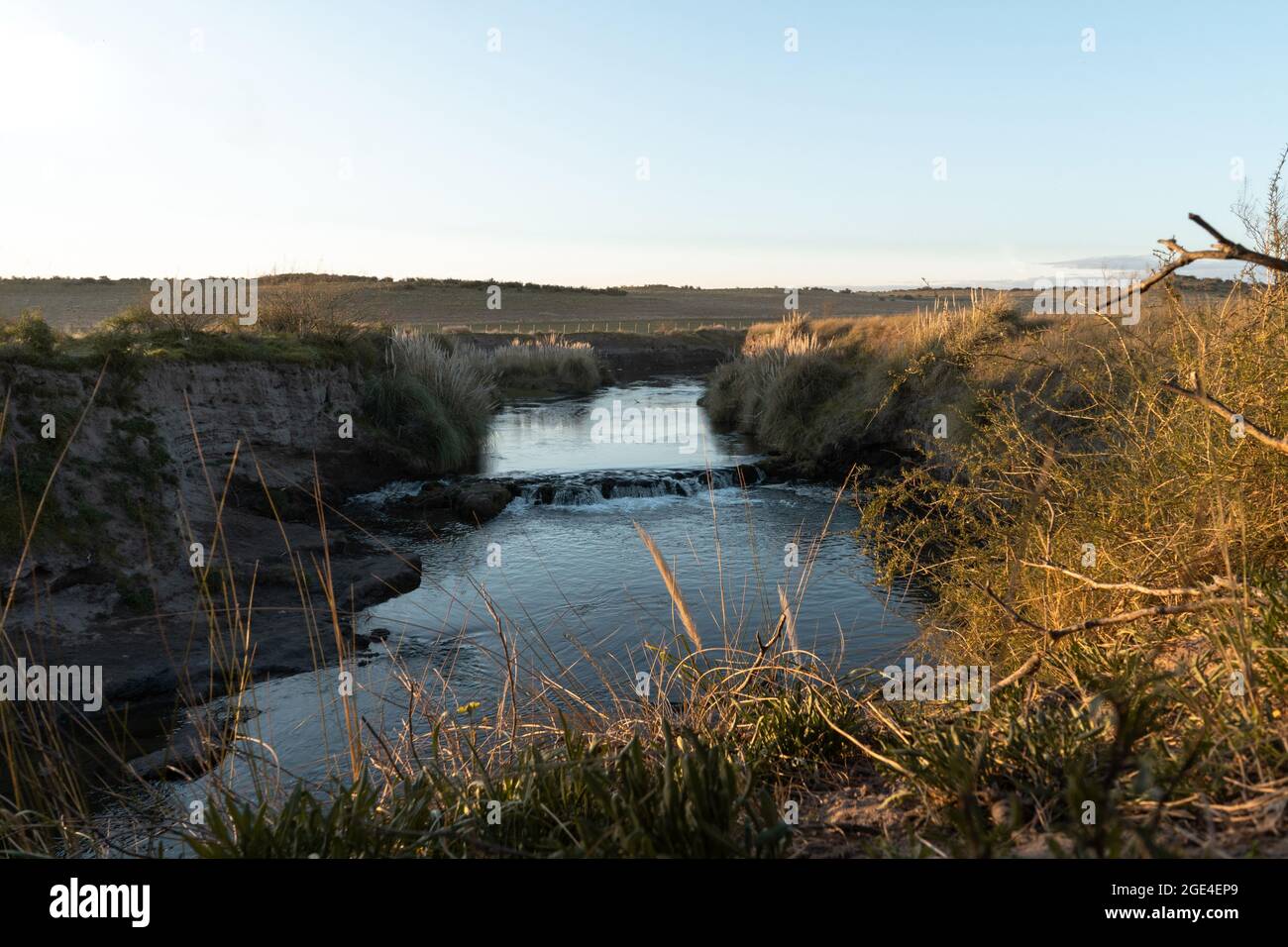 Water stream with a small waterfall in the middle of an agricultural ...