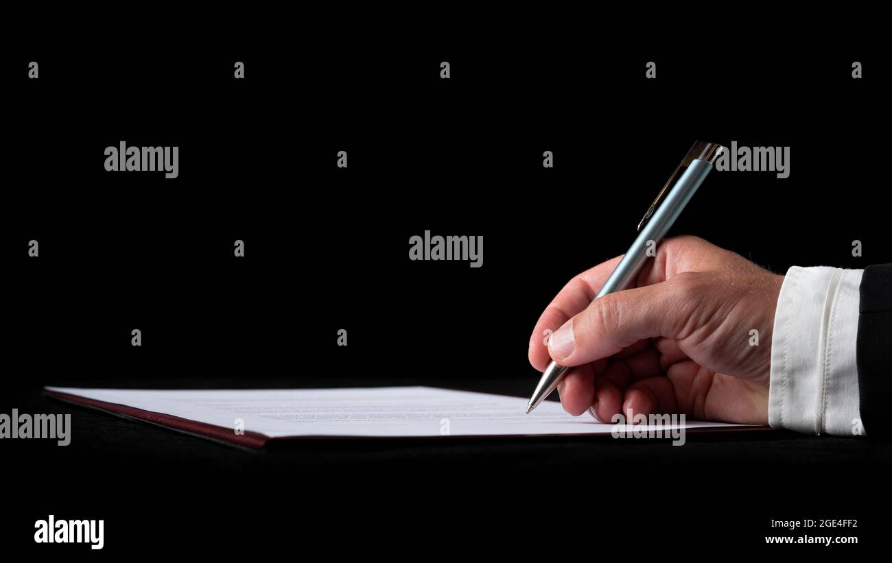 Hand of a businessman signing a document or contract on black desk over ...