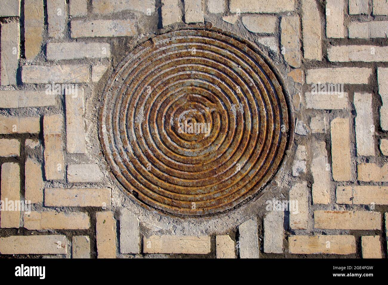iron rusty round manhole on the sidewalk paved with stone tiles top ...