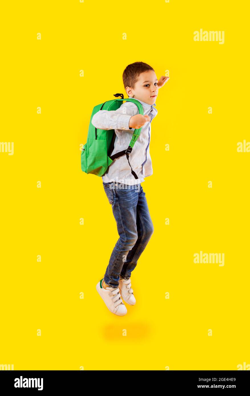 Jumping emotional schoolboy on the yellow background Stock Photo - Alamy