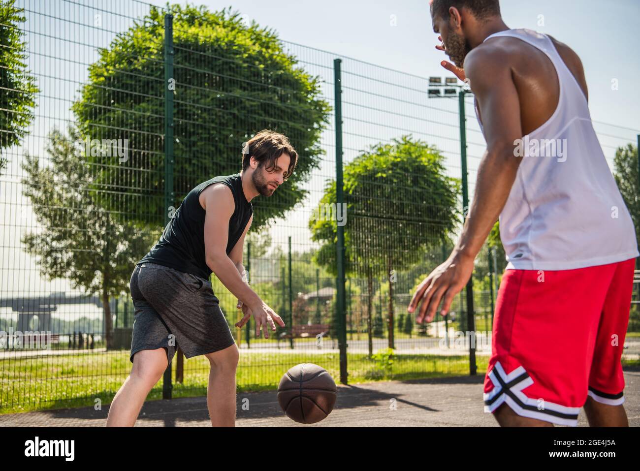 Young man running near basketball ball and blurred african american ...