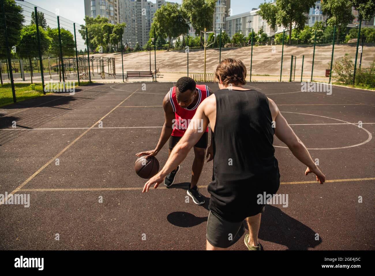 Multiethnic men playing basketball on outdoor playground at daytime ...