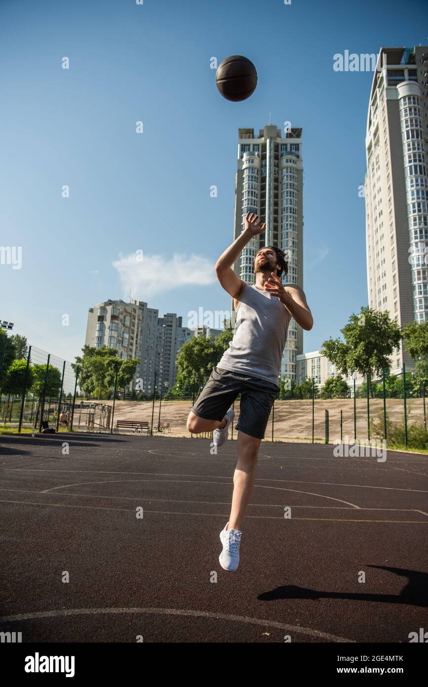 Player jumping and throwing basketball ball on court at daytime Stock ...
