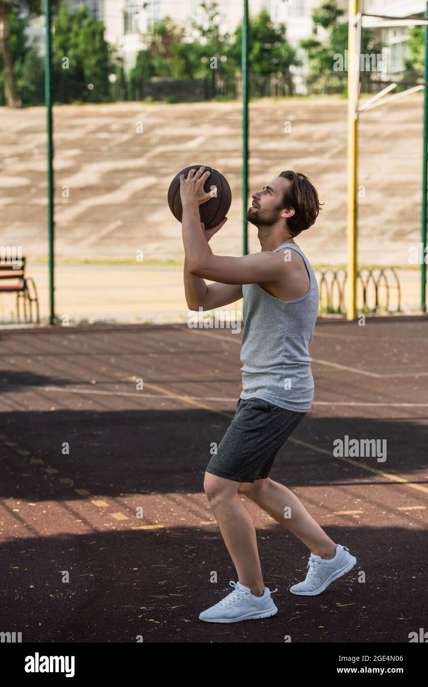 Side view of young man holding basketball ball on outdoor playground ...