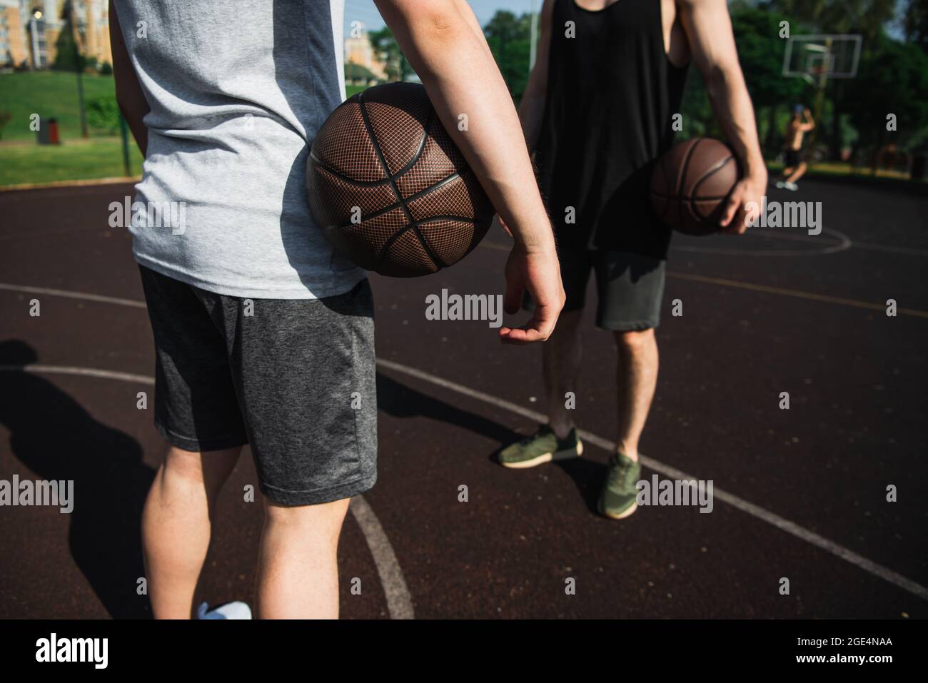 Cropped view of men holding basketball balls on playground Stock Photo ...
