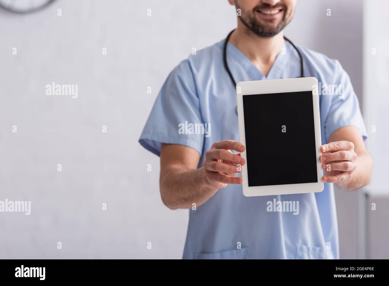 cropped view of smiling doctor in blue uniform holding digital tablet ...