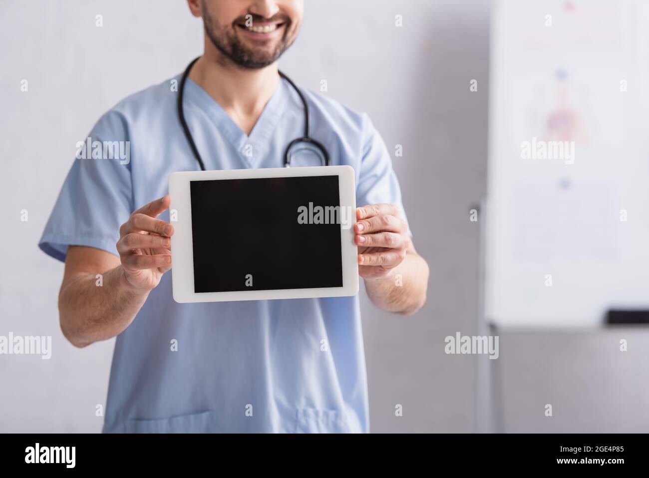 partial view of smiling doctor showing digital tablet with blank screen ...
