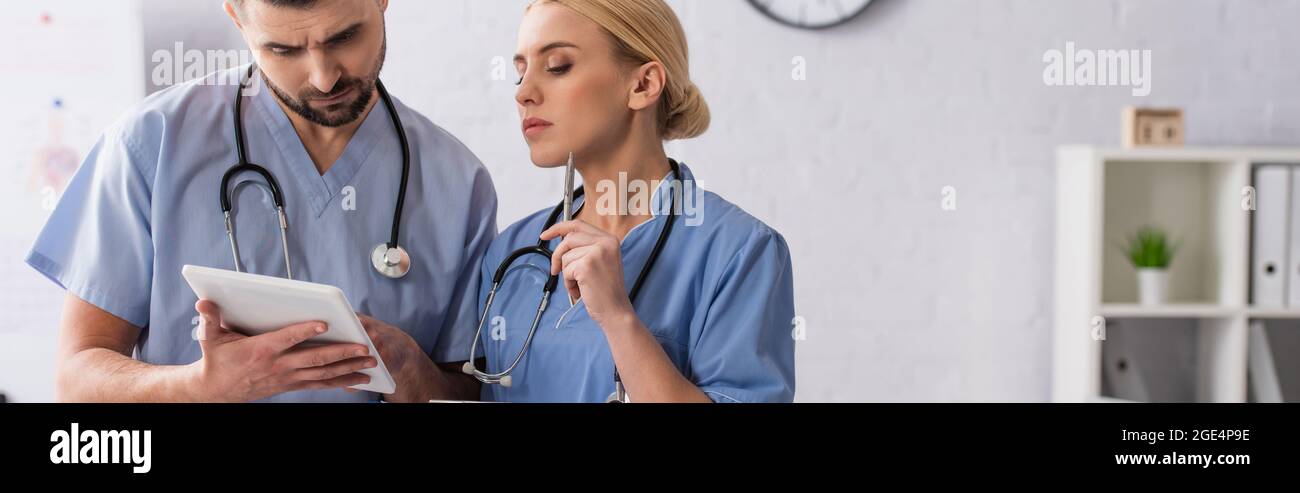 serious doctors in blue uniform looking at digital tablet in hospital ...
