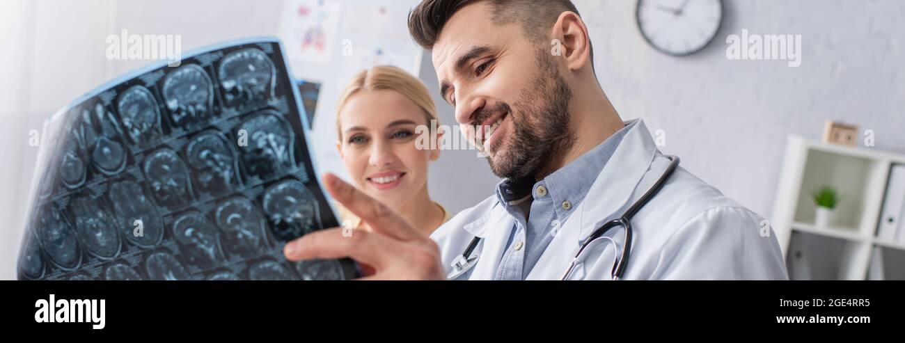 positive doctor looking at brain mri scan near happy woman, banner ...