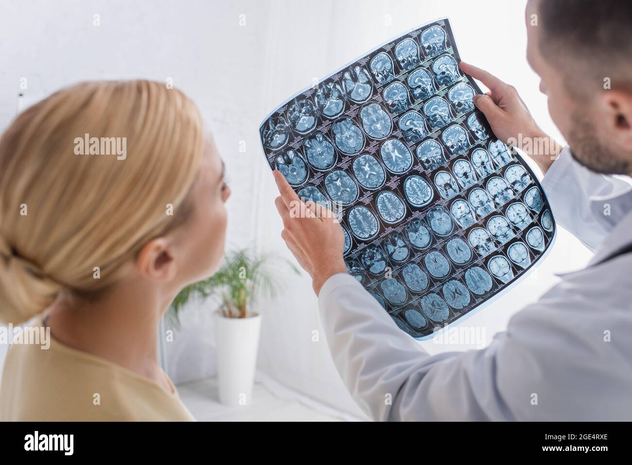 physician showing mri scan to patient in clinic on blurred foreground ...