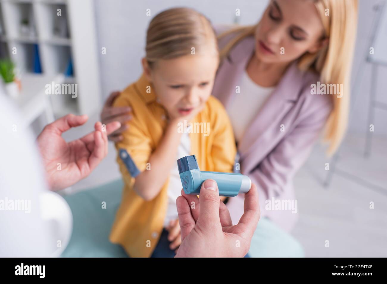 Doctor holding inhaler near sick kid and mother on blurred background ...