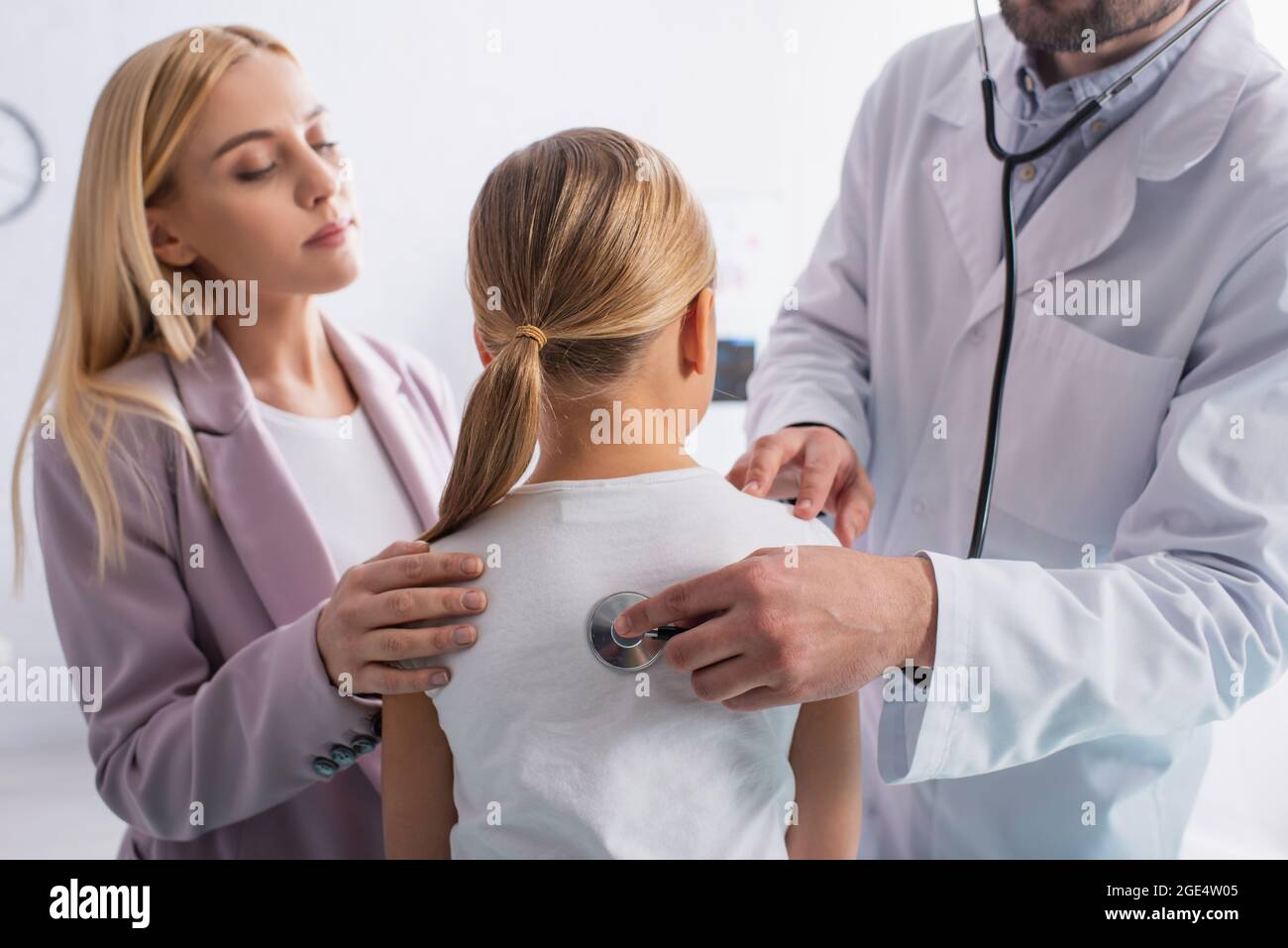 Pediatrician using stethoscope on back of child in clinic Stock Photo ...