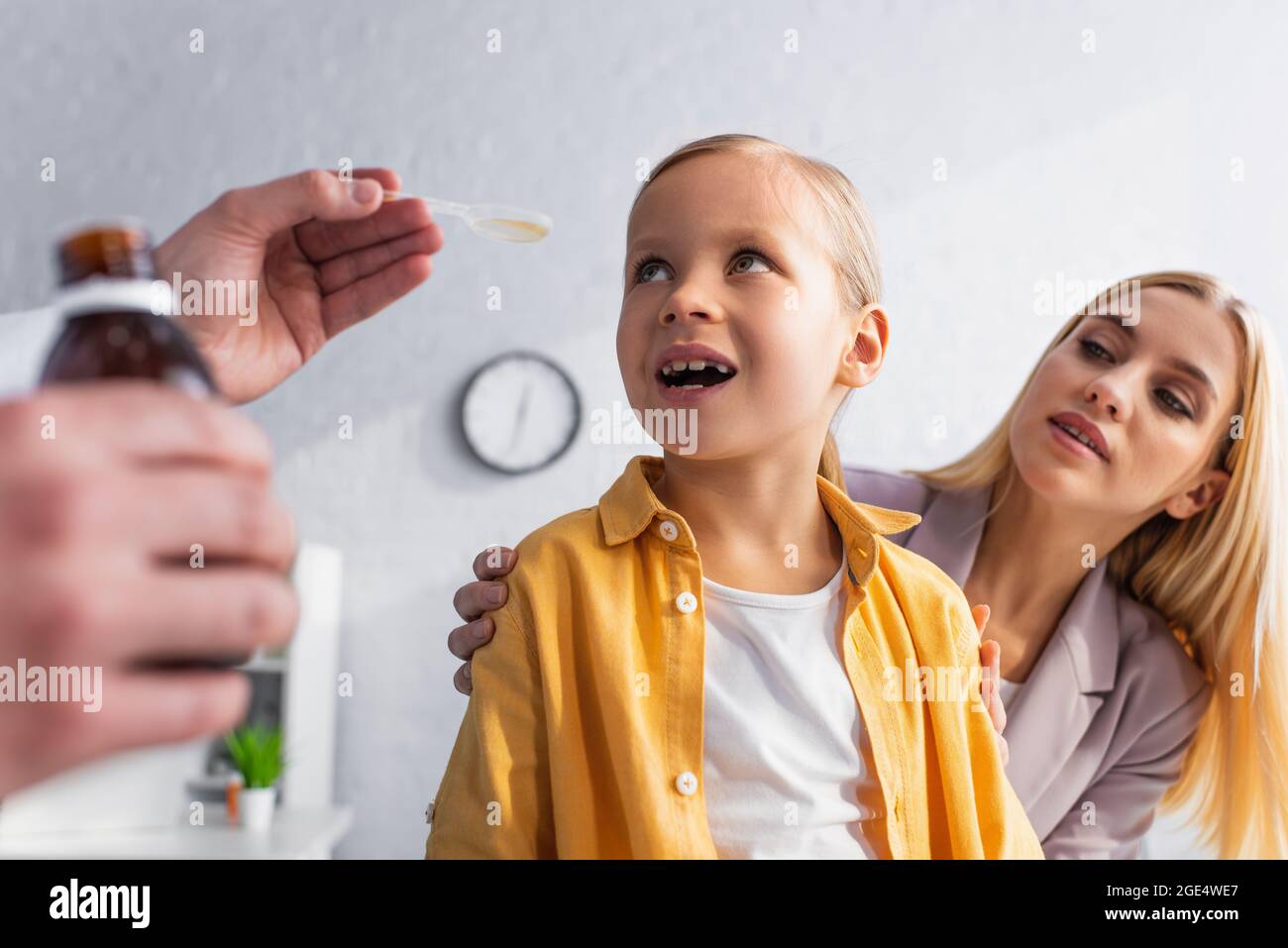 Pediatrician holding syrup near woman hugging kid in clinic Stock Photo ...