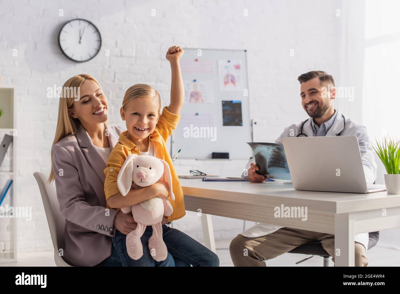 Happy kid with soft toy showing yes gesture near parent and doctor with ...