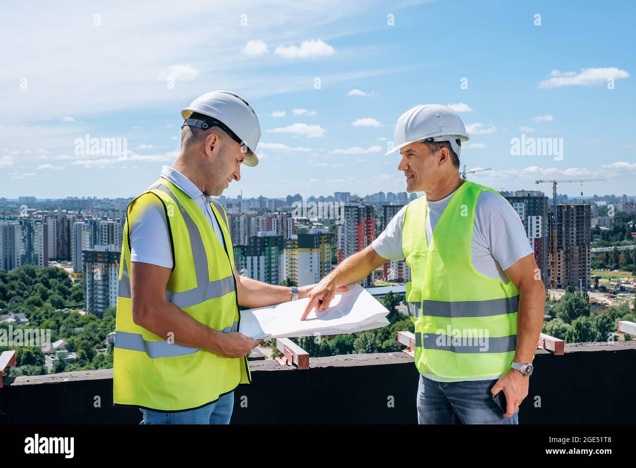 Male engineers reading blueprint together Stock Photo - Alamy