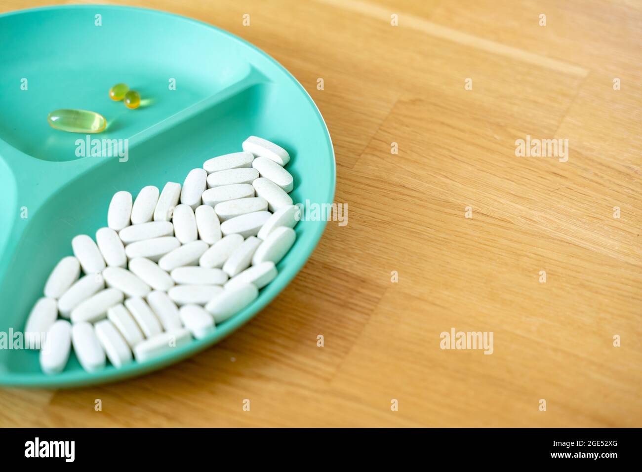 Green plate with dividers filled with pills and capsules. Biohacking ...