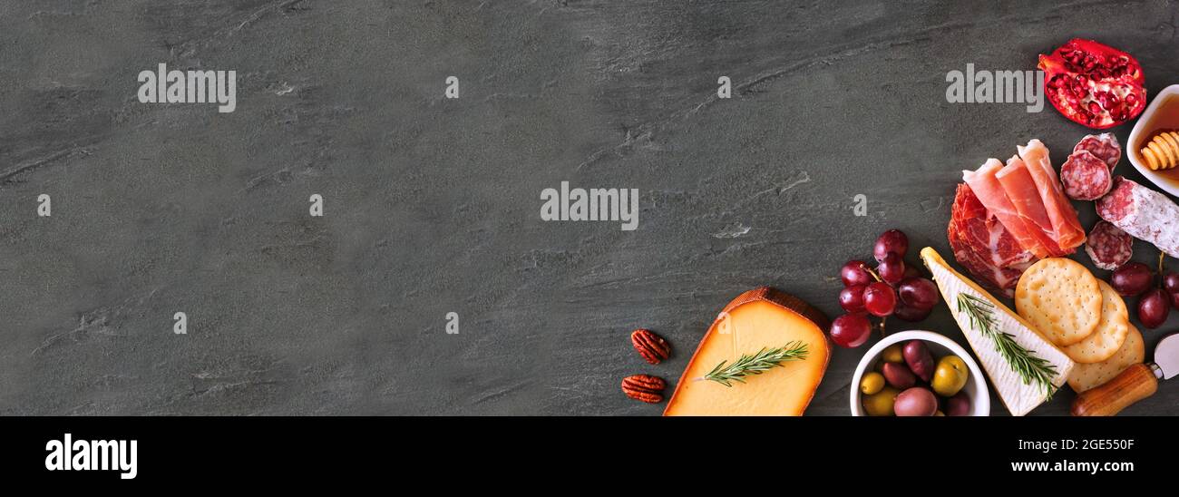 Selection of cheese and meat appetizers. Corner border banner, above ...