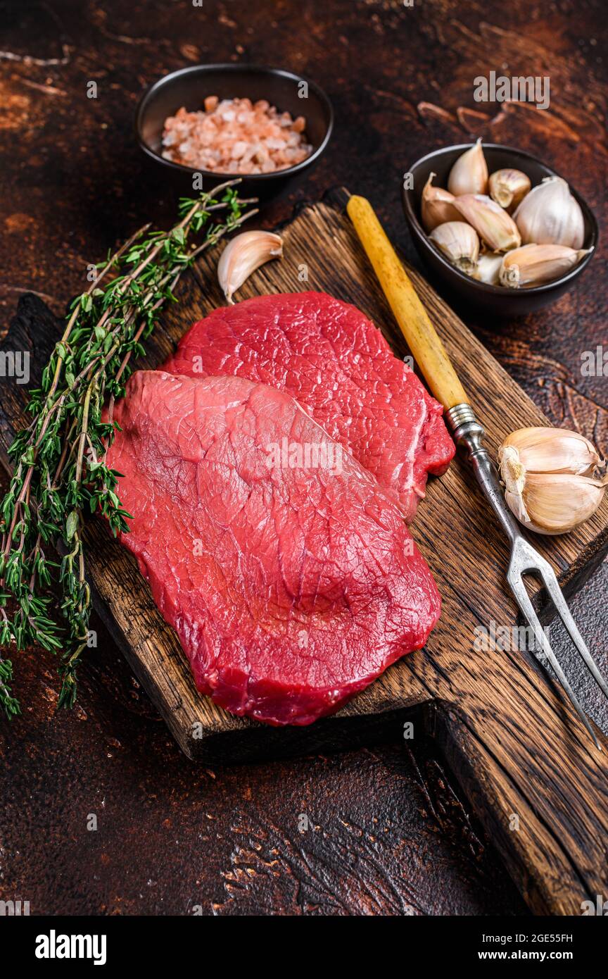 Raw rump beef meat steaks on butcher wooden board. Dark background. Top ...