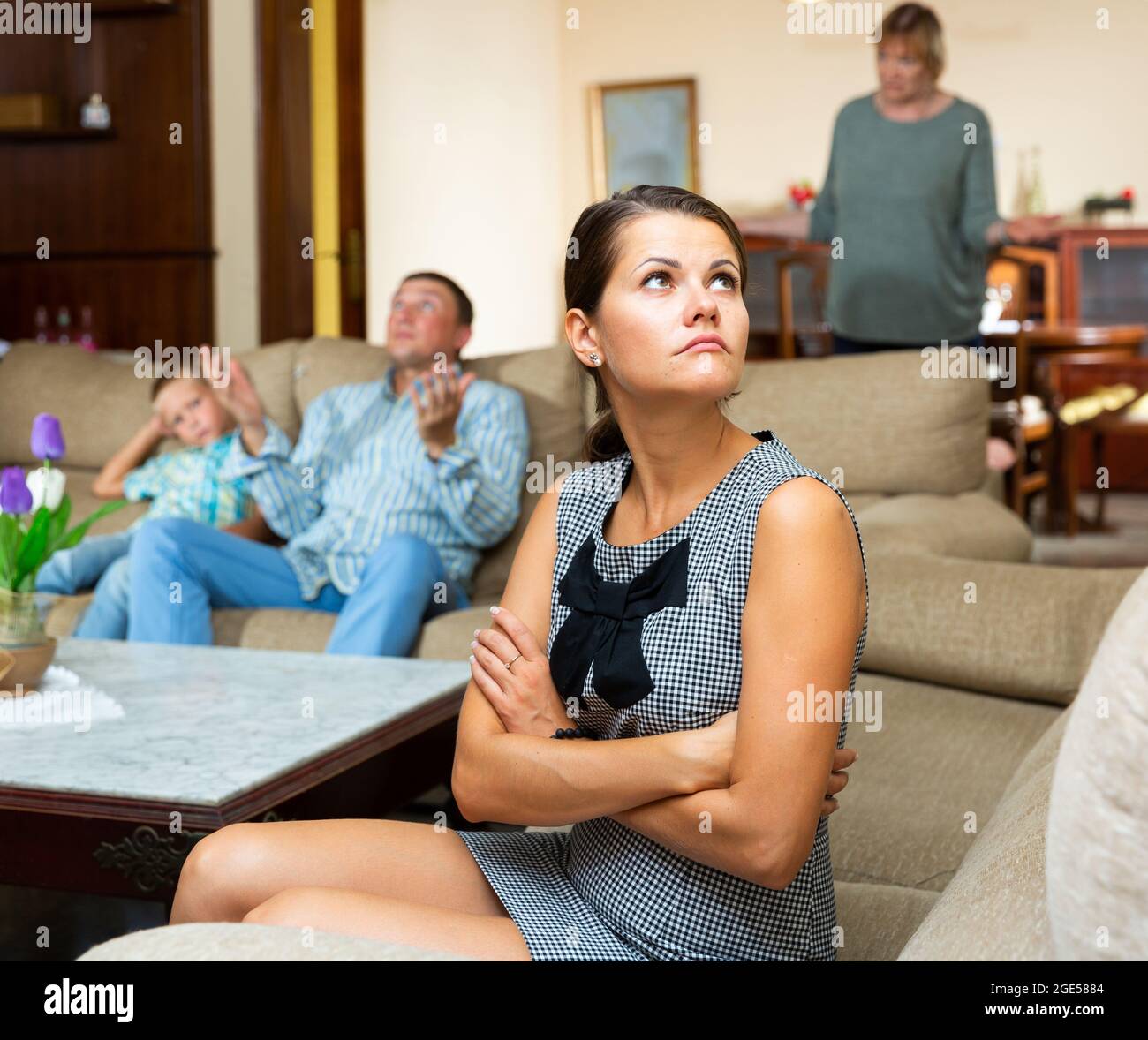 Upset woman sitting during quarrelling between family on background ...
