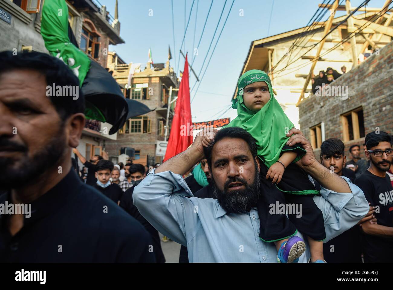 Srinagar, India. 16th Aug, 2021. A man carries a kid over his shoulder ...