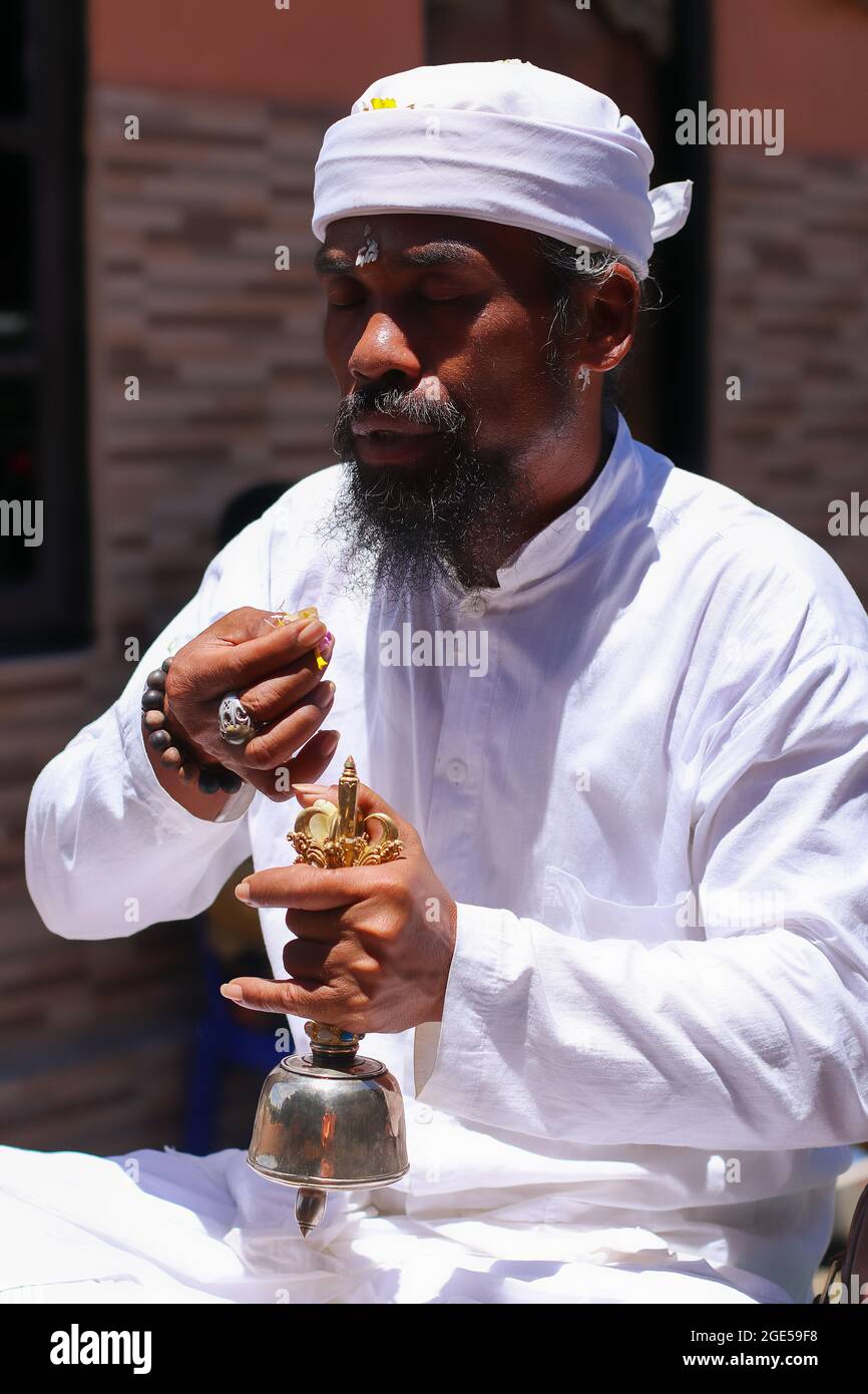 Balinese Hindu priest holding the bell while leading the prayer Stock ...