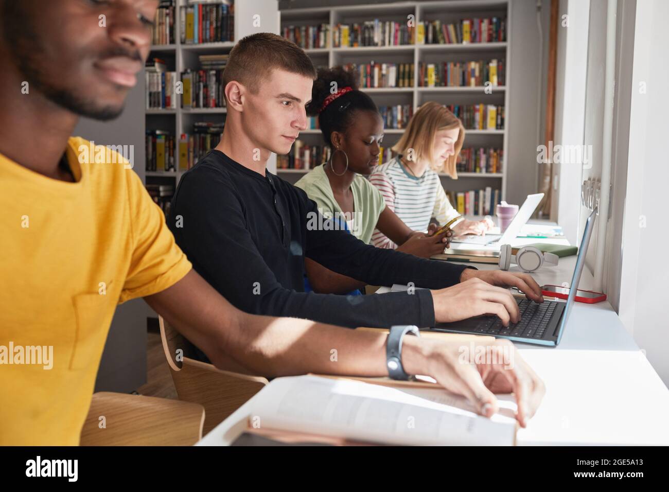 Side view at diverse group of students sitting in row while studying in ...