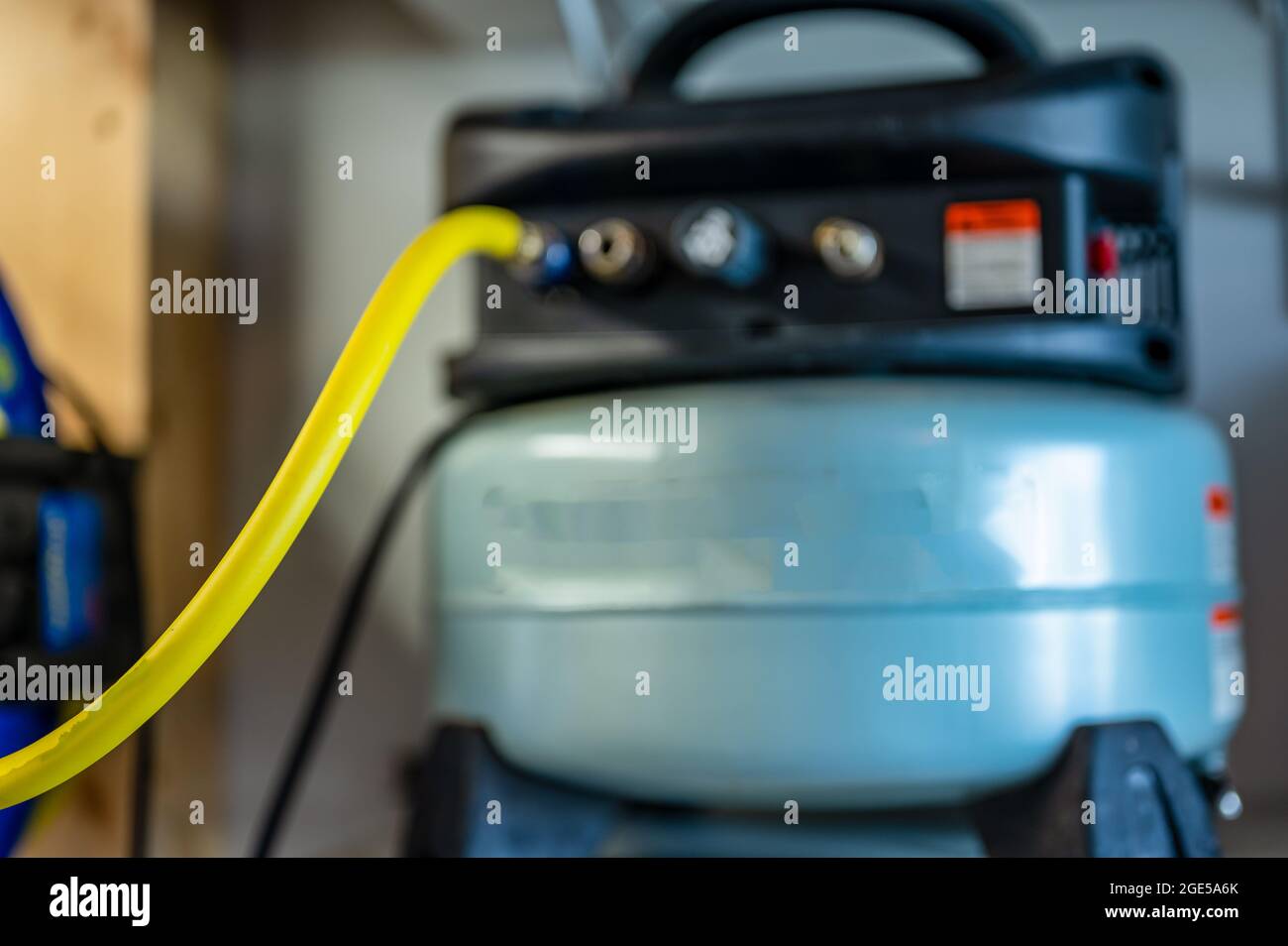 Selective focus on a hose connected to a Pancake air compressor sitting ...