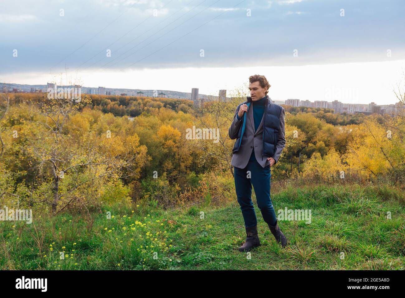 Tall handsome man walking outdoor in yellow autumn forest on the hill ...