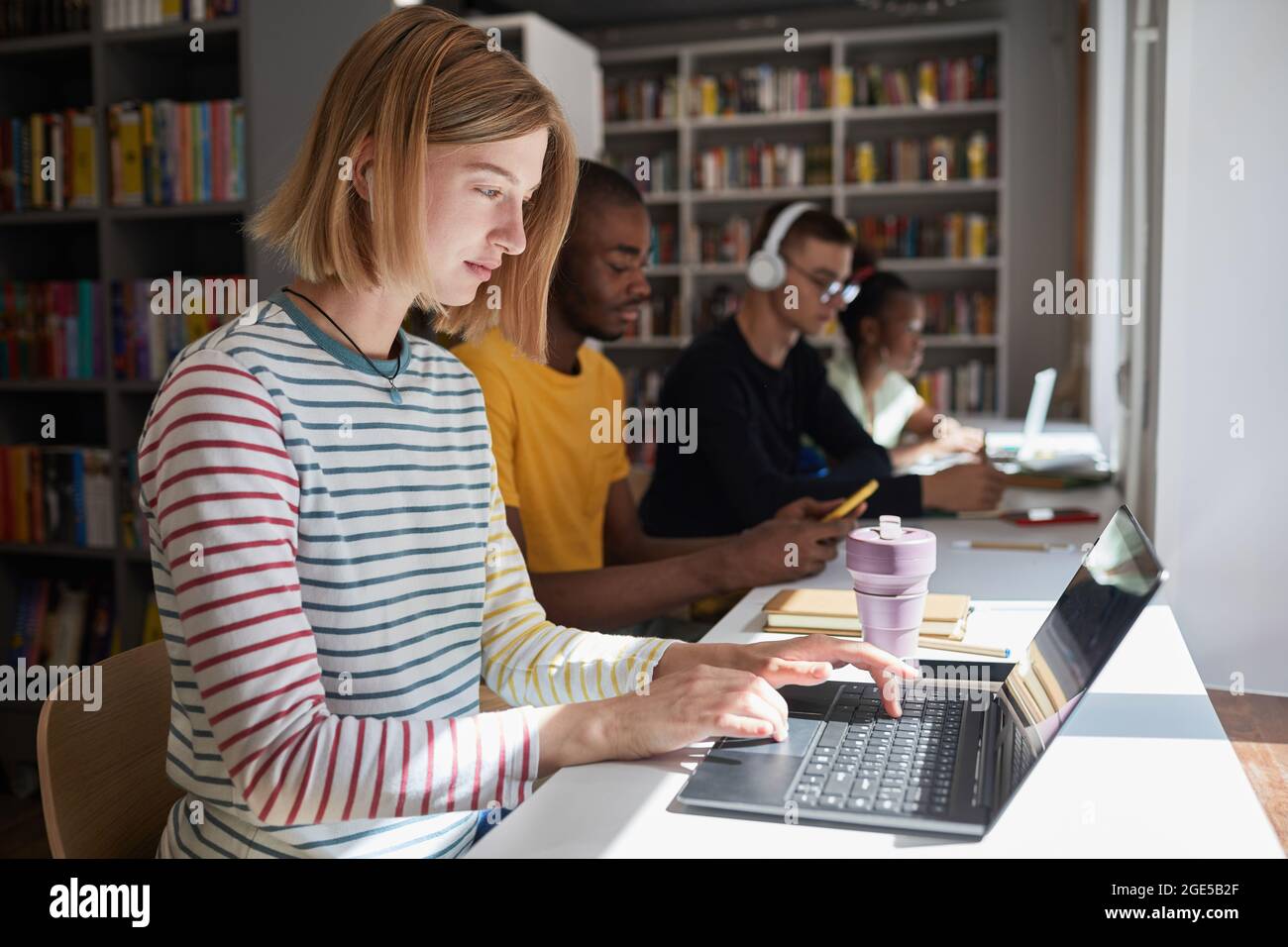 Side view portrait of young woman studying with group of students in ...