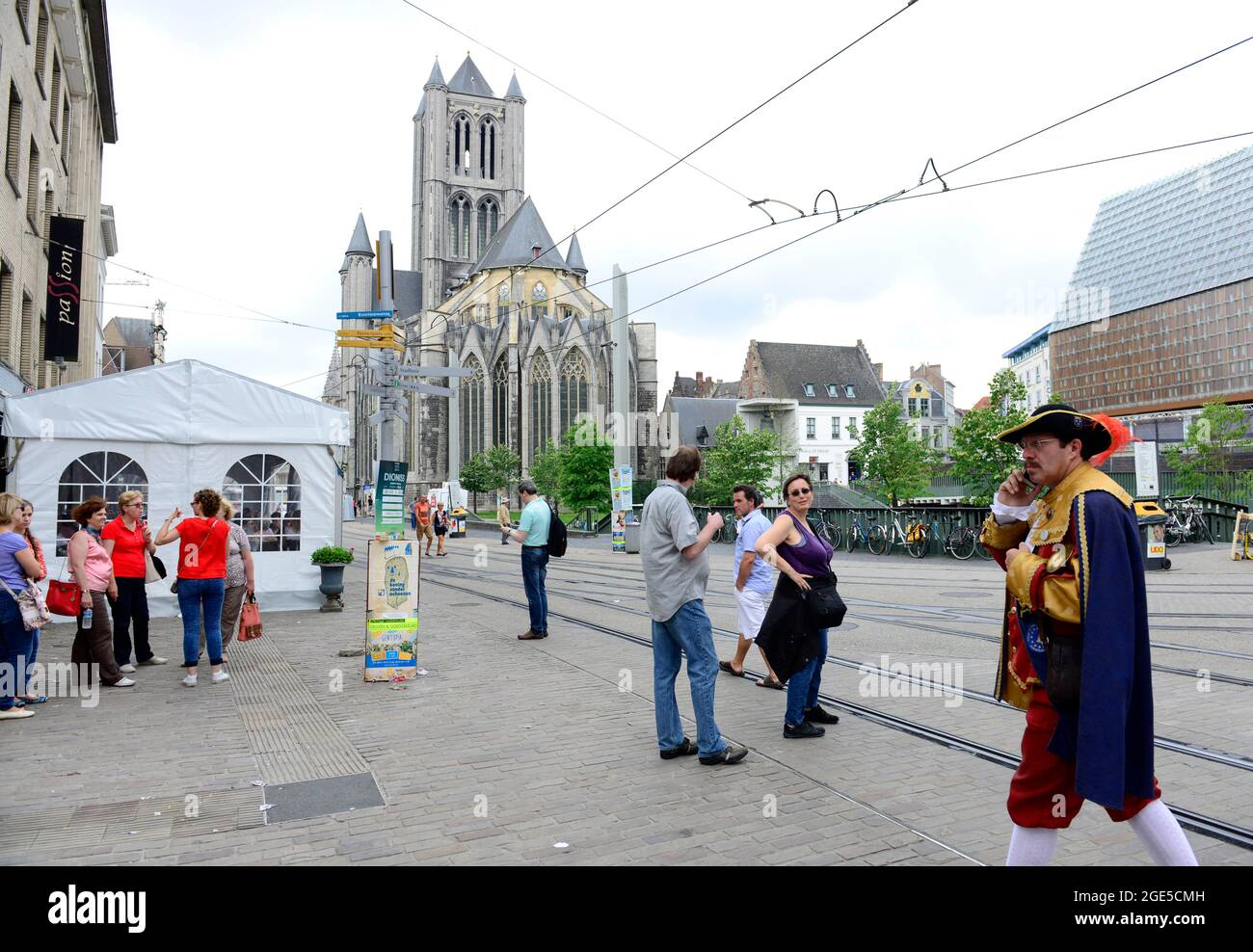 Traditionally dressed Belgian man walking by the Belfry of Ghent ...