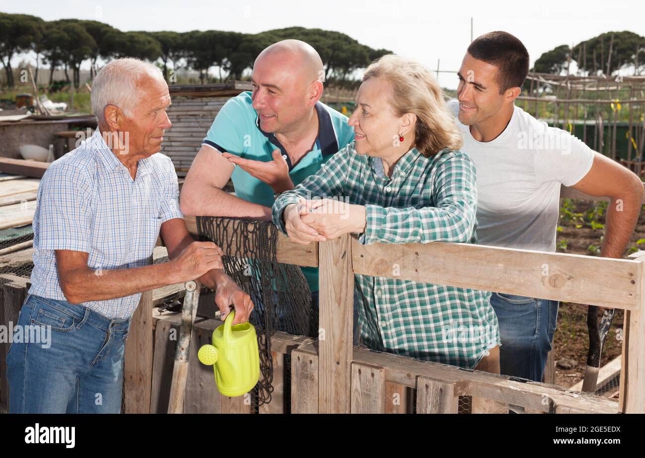 Farm neighbors talk at the border of the garden plot Stock Photo - Alamy